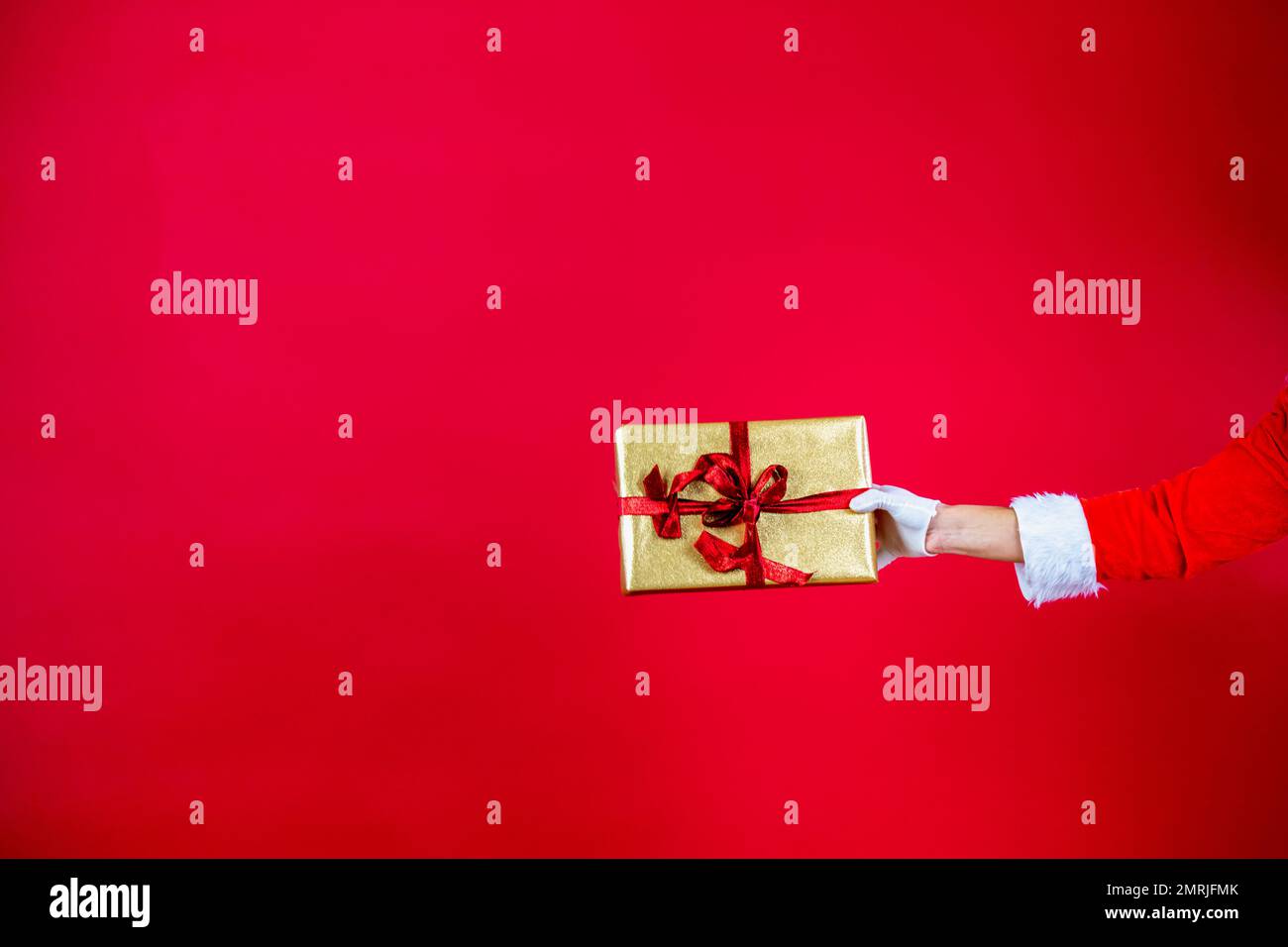 A view of the Santa Clause's hand holding a gift on a red background ...