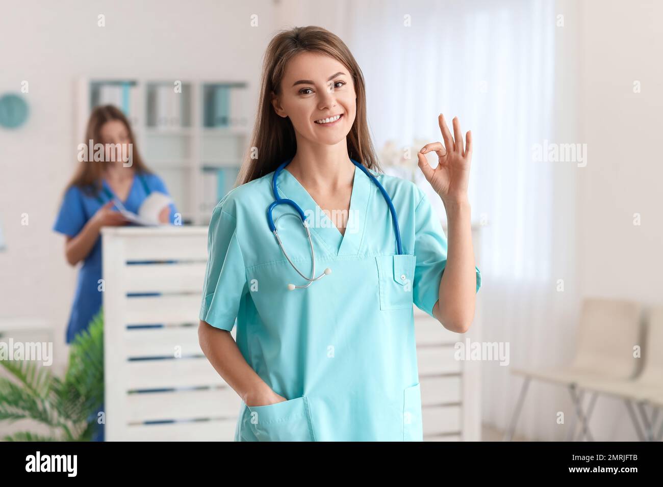 Female medical assistant with stethoscope showing OK in clinic Stock ...