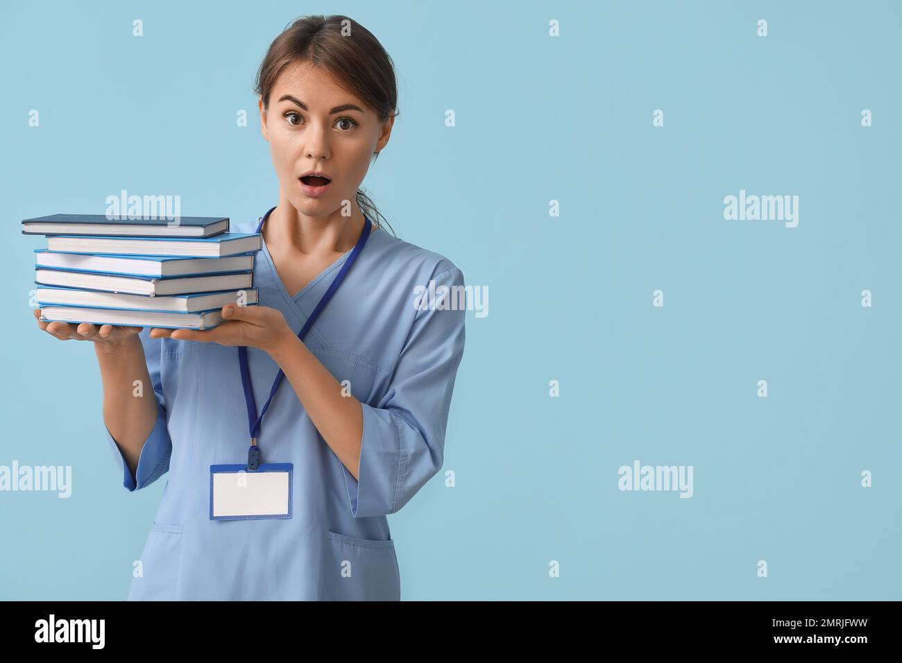Shocked female medical intern with books on blue background Stock Photo ...