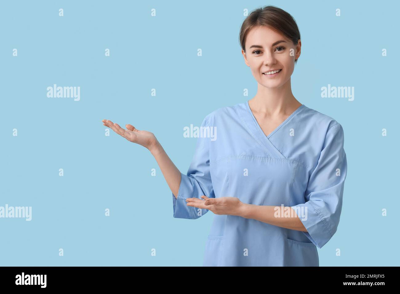 Female medical intern showing something on blue background Stock Photo ...