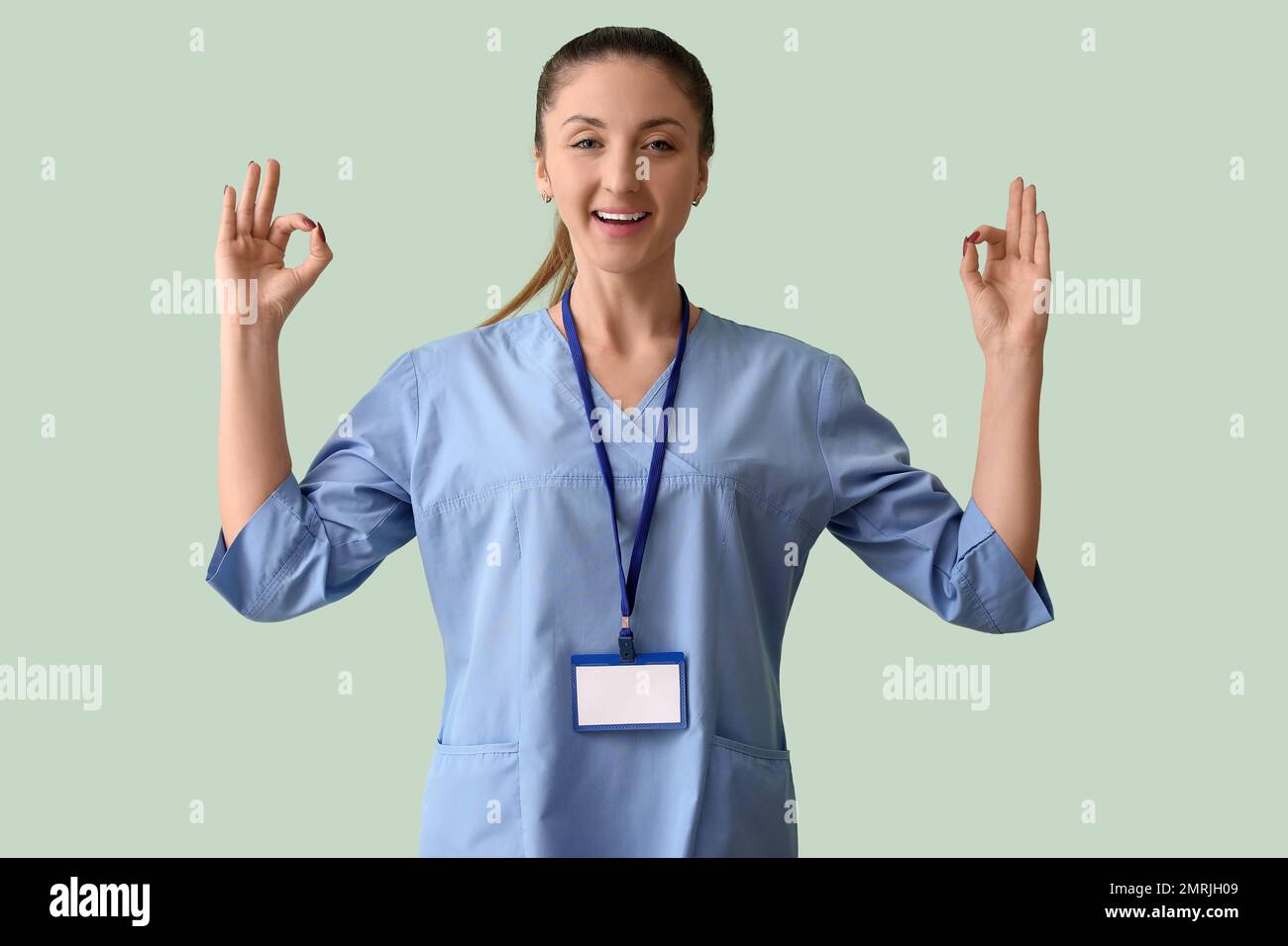 Female medical intern with badge showing OK on green background Stock ...