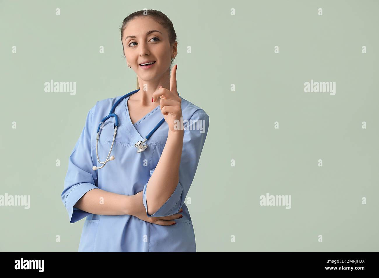 Female medical intern with stethoscope pointing at something on green ...