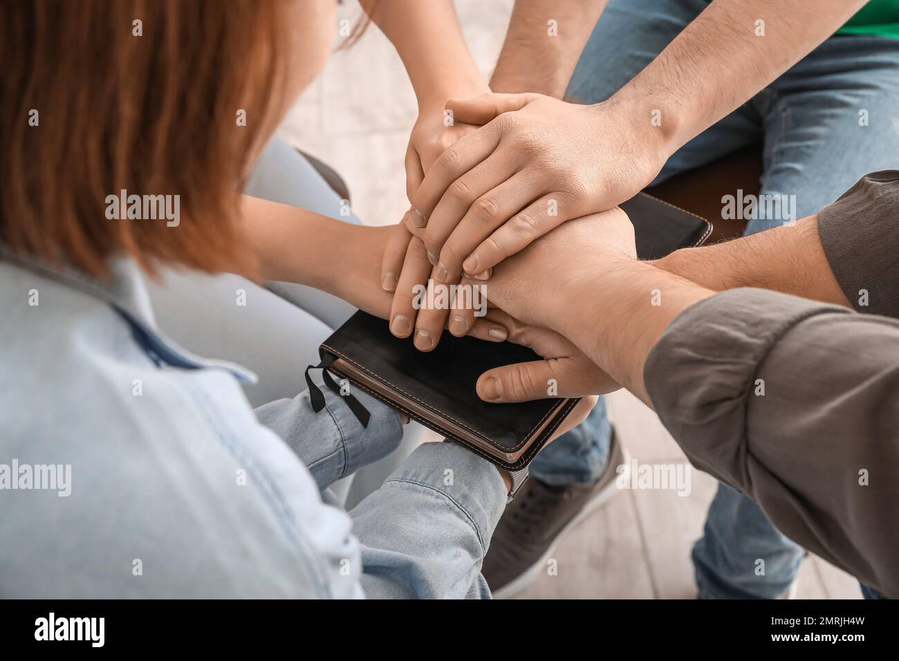 Group of people praying with Holy Bible in room, closeup Stock Photo ...