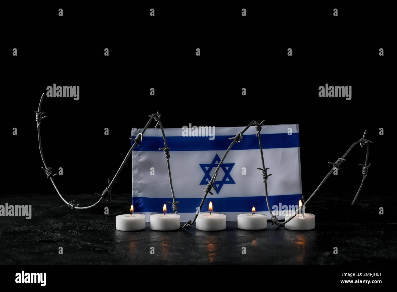 Burning candles, flag of Israel and barbed wire on dark background with ...