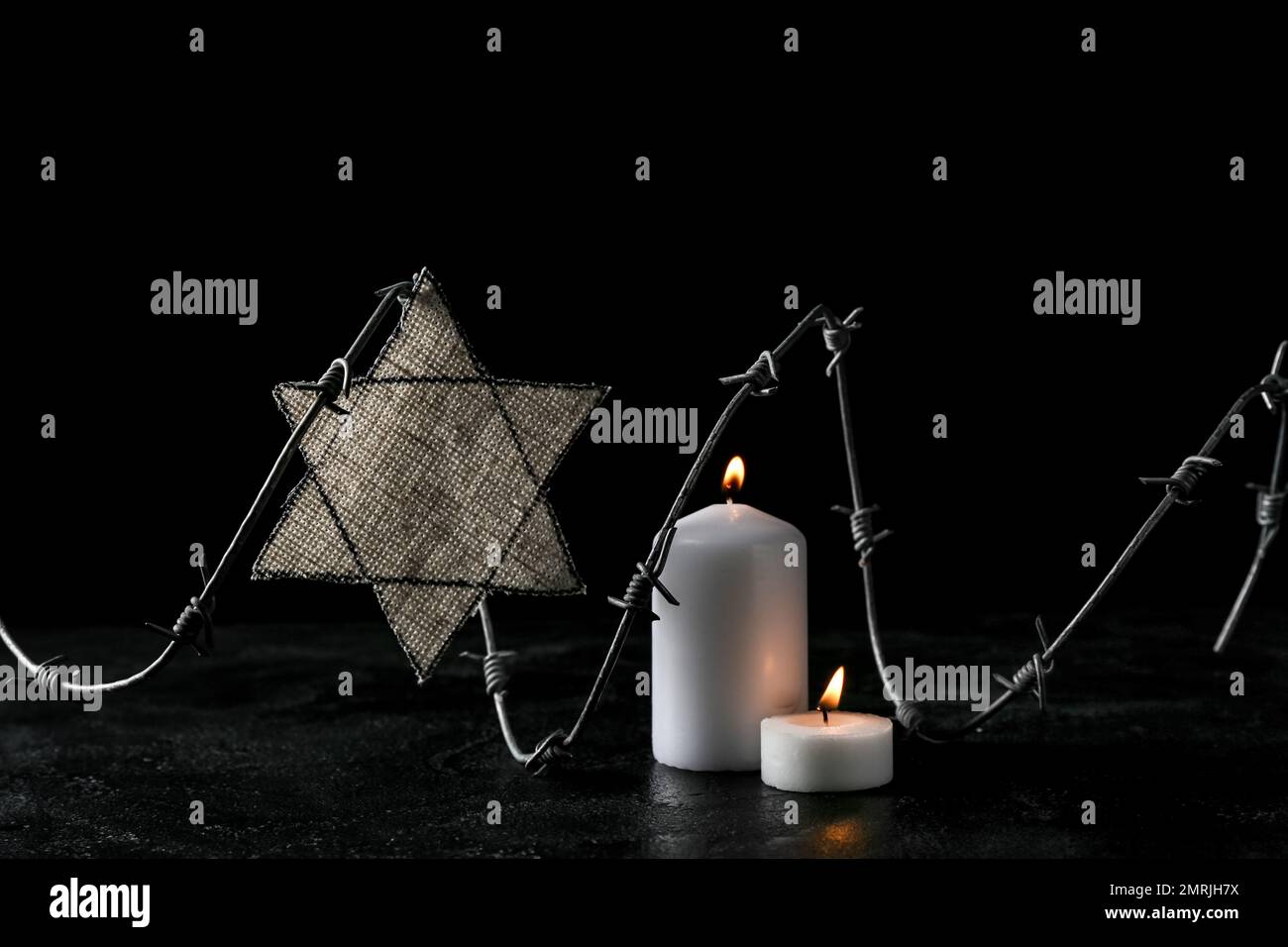 Burning candles, Jewish badge and barbed wire on dark background ...