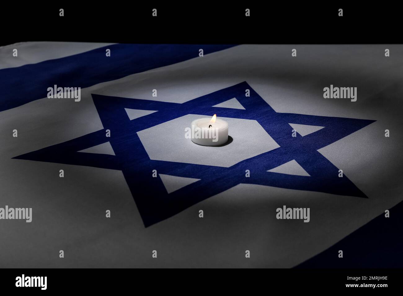 Burning candle on flag of Israel against dark background. International ...