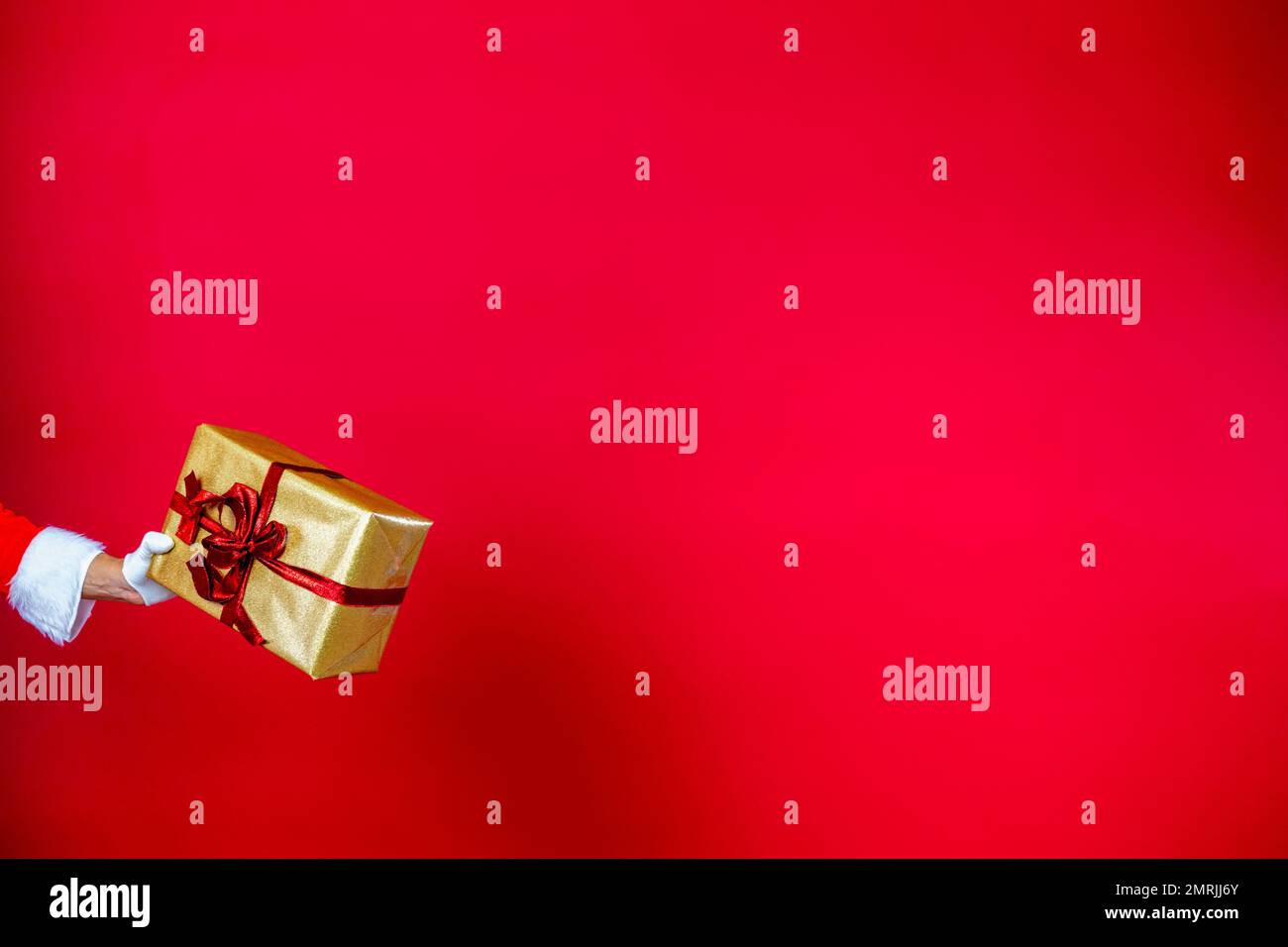 A view of the Santa Clause's hand holding a gift on a red background ...