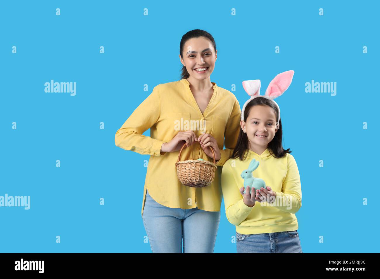 Beautiful woman and her little daughter with Easter eggs and rabbit on ...