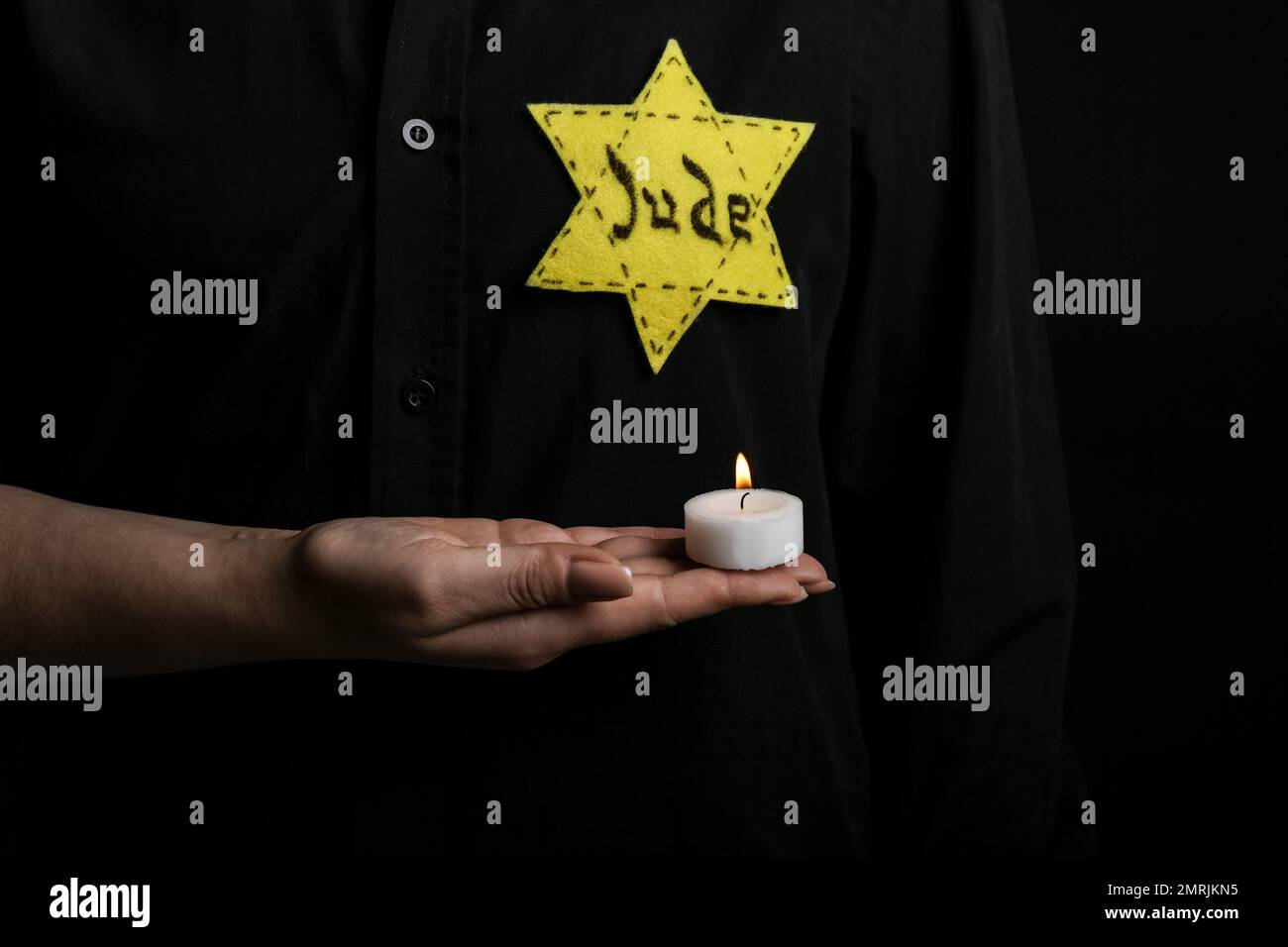 Jewish woman with yellow badge and burning candle on dark background ...