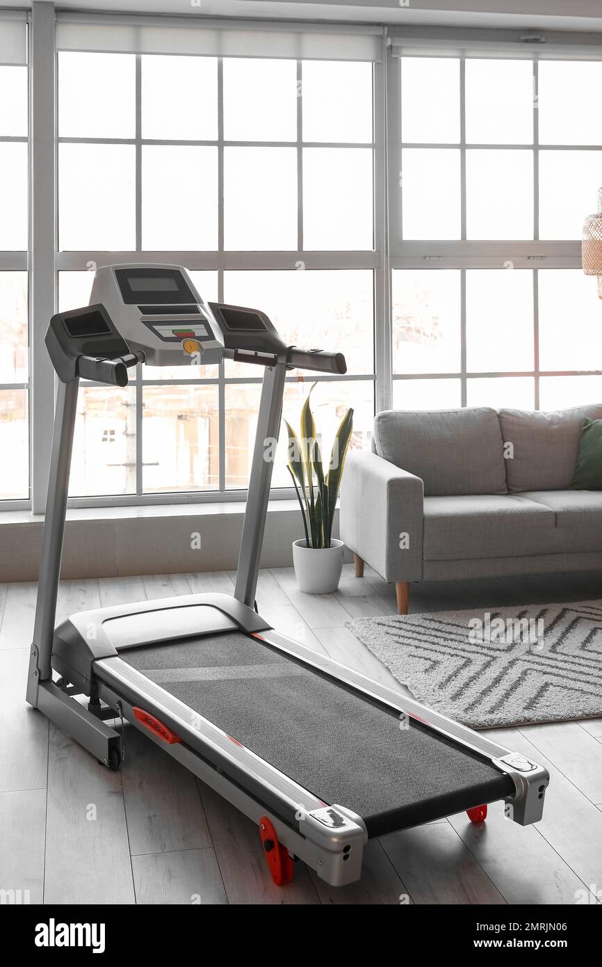 Interior of living room with modern treadmill near window Stock Photo ...