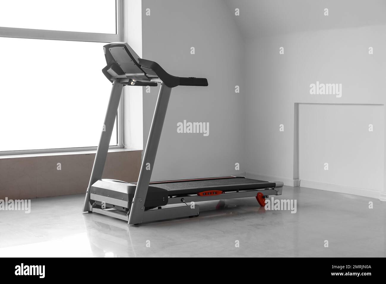 Interior of room with modern treadmill near window Stock Photo - Alamy