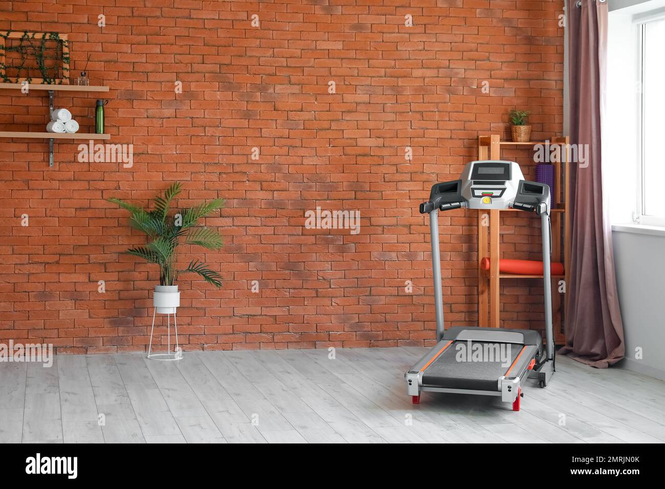 Interior of room with modern treadmill near brick wall Stock Photo - Alamy