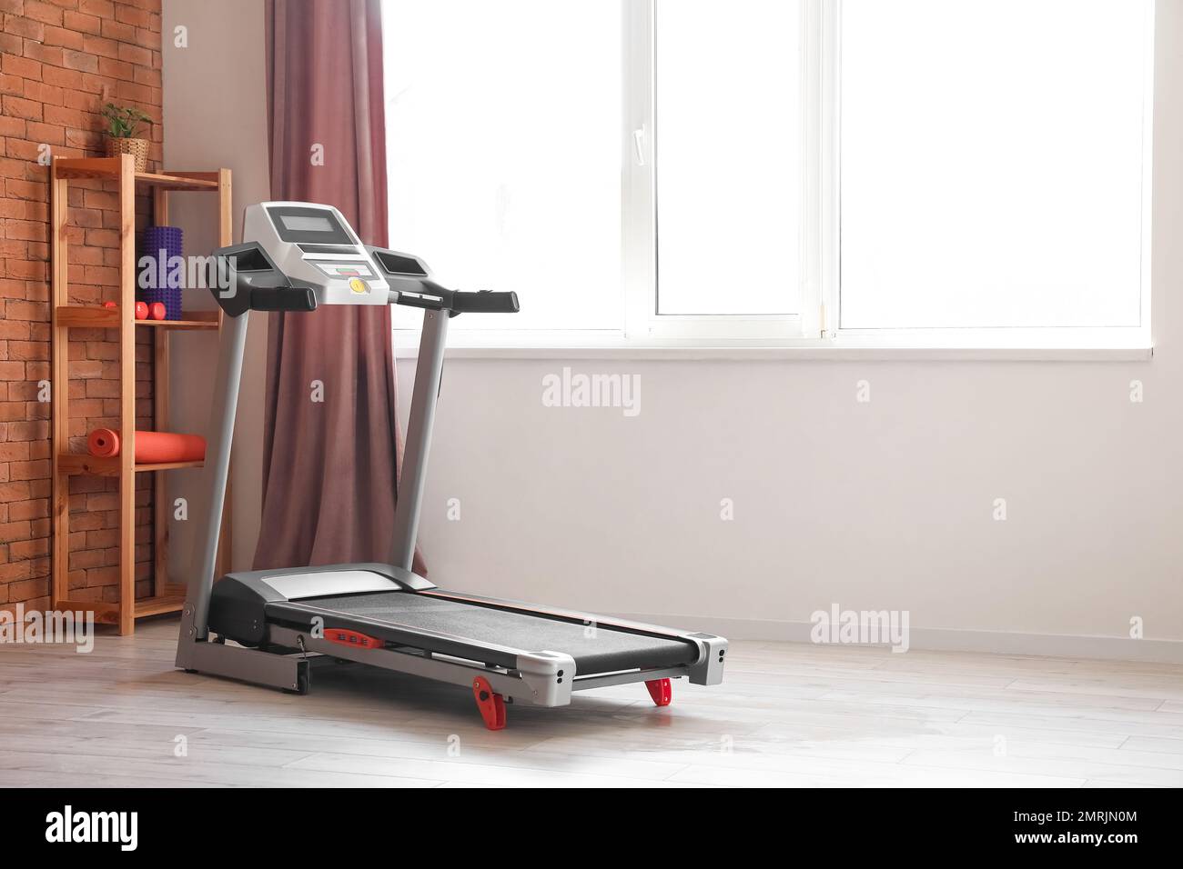 Interior of room with modern treadmill near window Stock Photo - Alamy