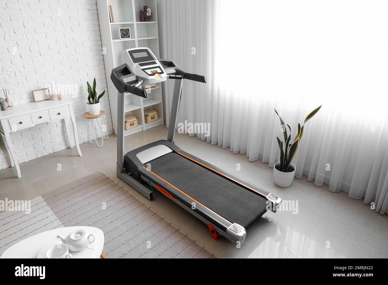 Interior of living room with modern treadmill near window Stock Photo ...