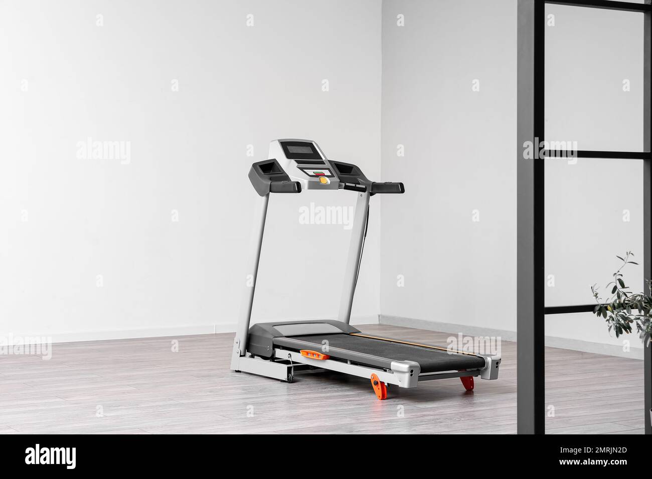Interior of room with modern treadmill near white wall Stock Photo - Alamy