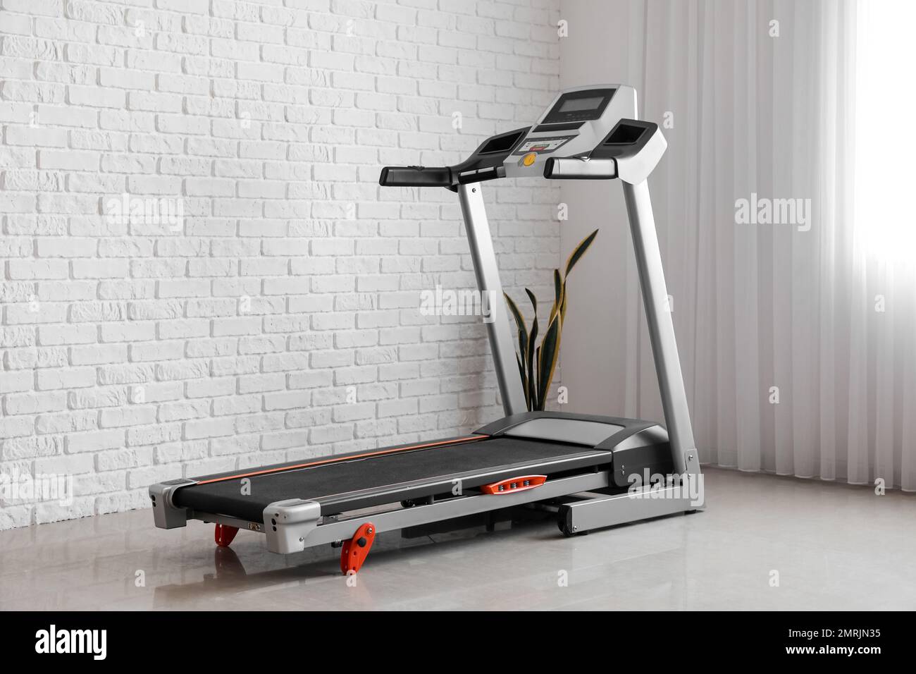 Interior of room with modern treadmill near white brick wall Stock ...