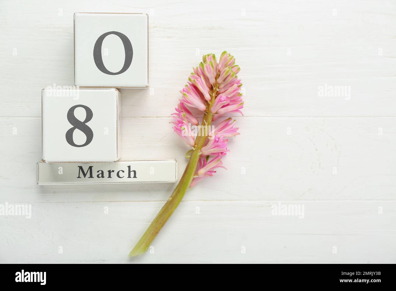 Cube calendar with date MARCH 8 and hyacinth flower on light wooden ...