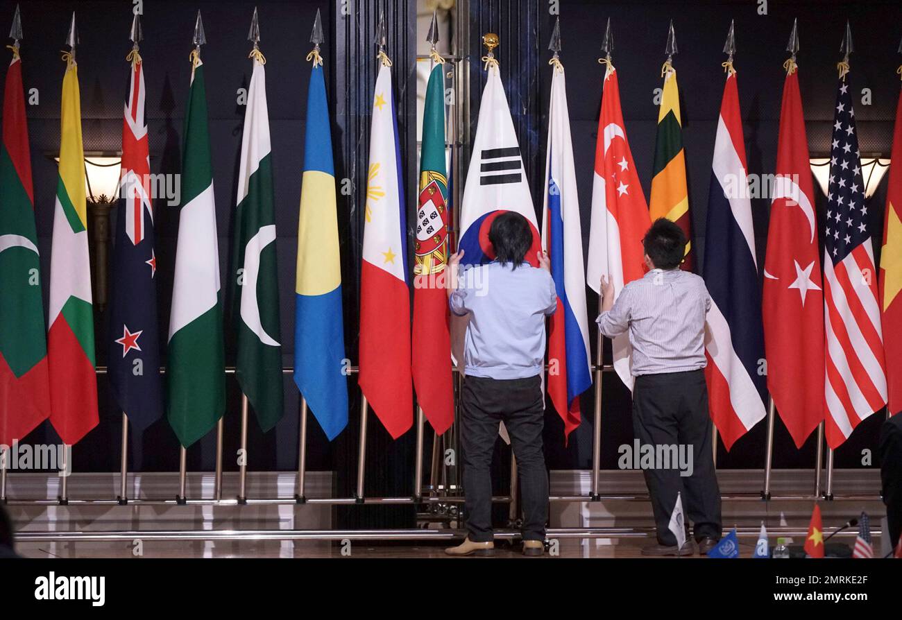 Staff members set up national flags prior to the opening session of the ...