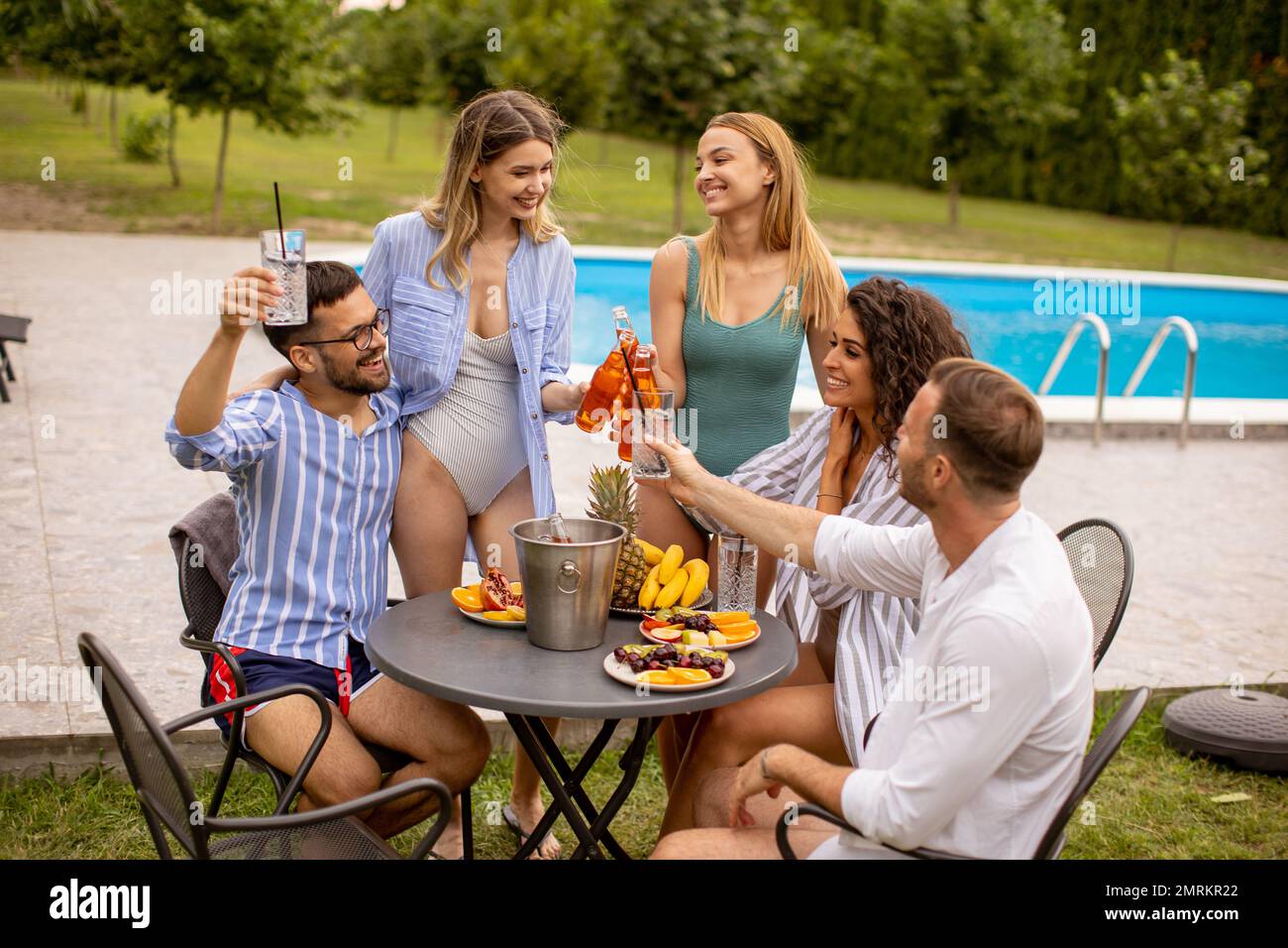 Group of happy young people cheering with cider by the pool in the ...