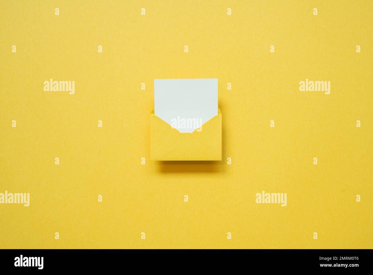 Yellow envelope with white blank card on yellow background. top view ...