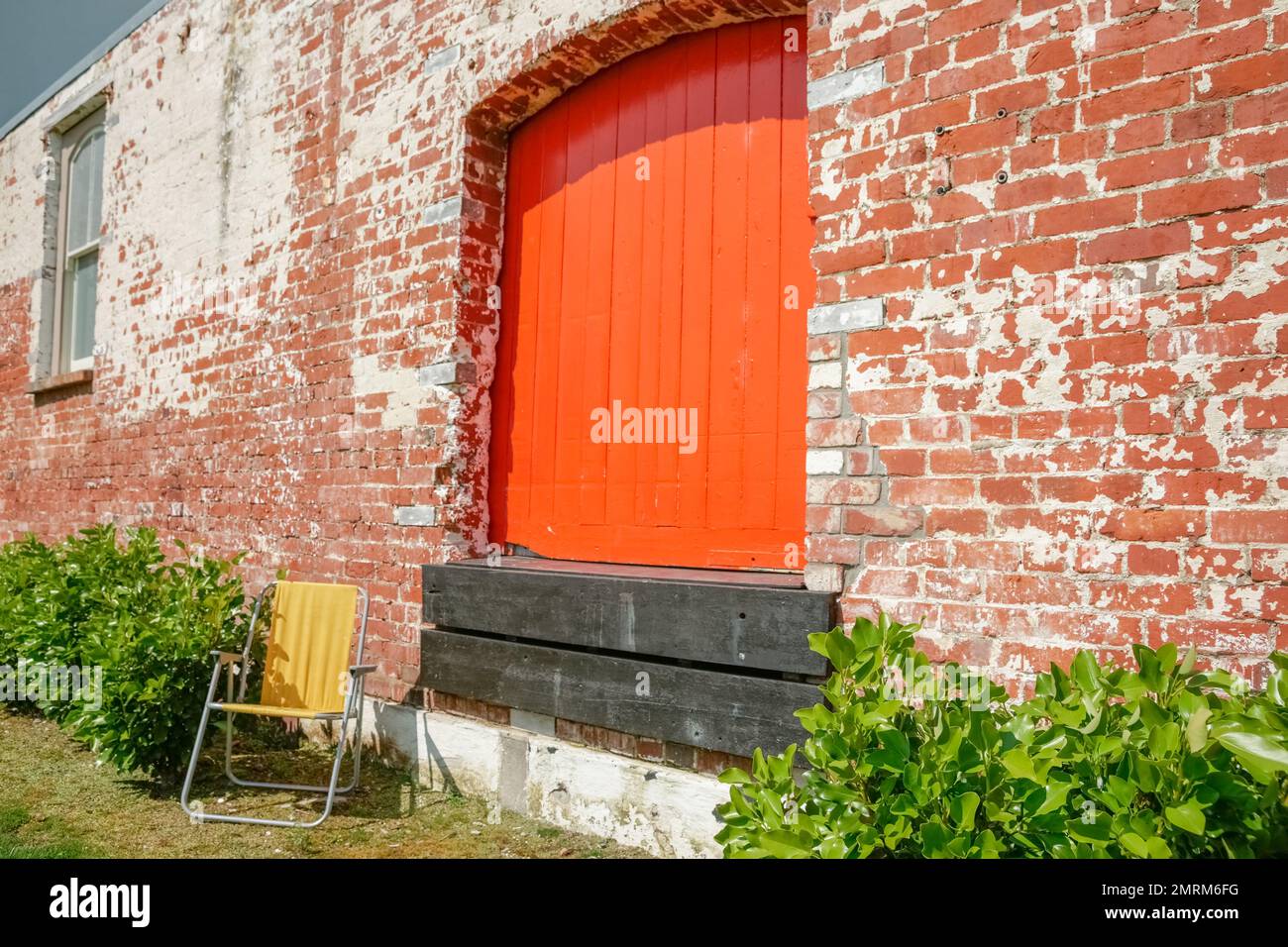 Red factory door in brick wall with empty yellow folding chair Stock ...