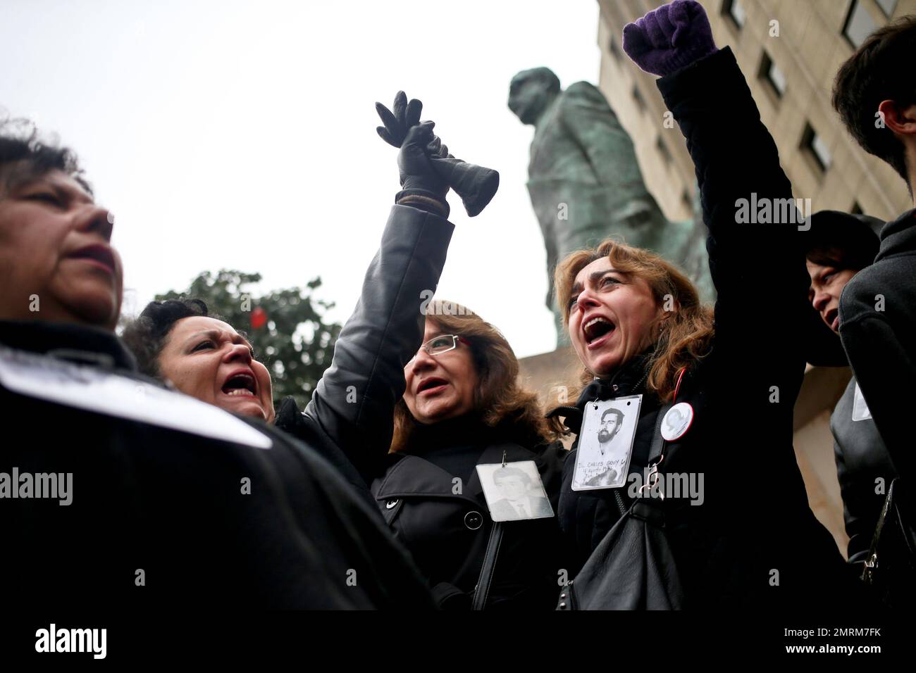 Women raise their arms in front of a statue of Chile's late President ...