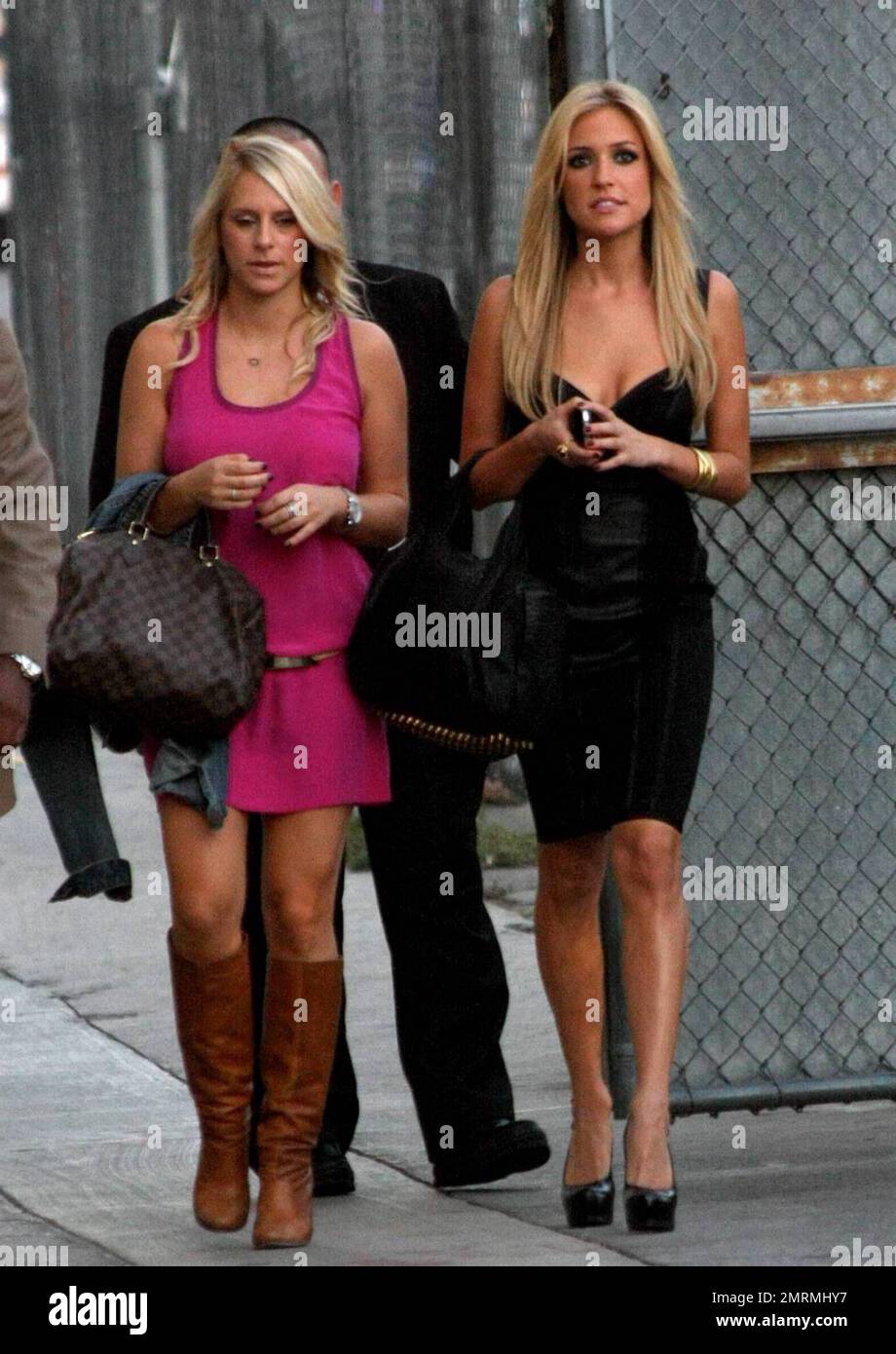 Kristin Cavallari wears a tight-fitting black dress and carries a ...