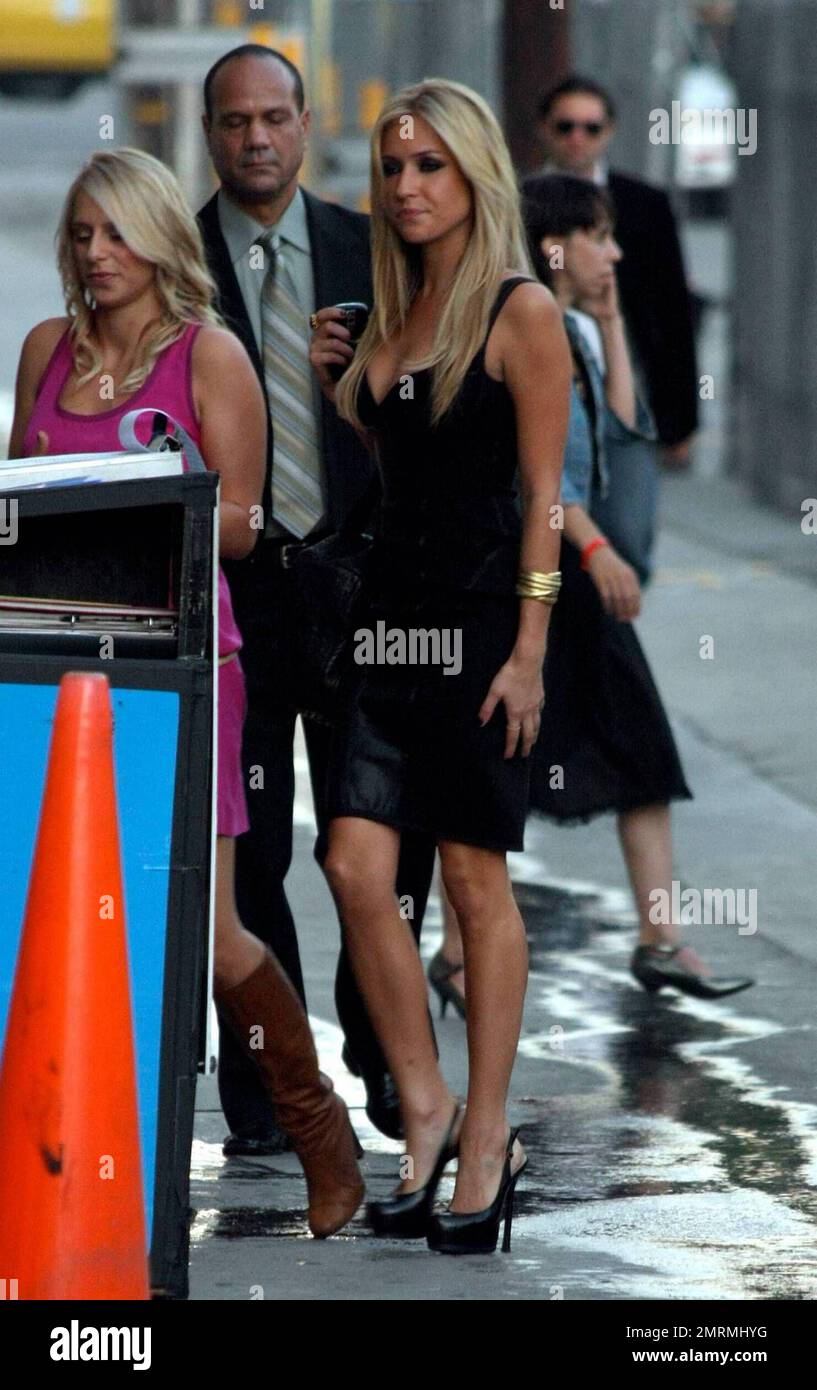 Kristin Cavallari wears a tight-fitting black dress and carries a ...