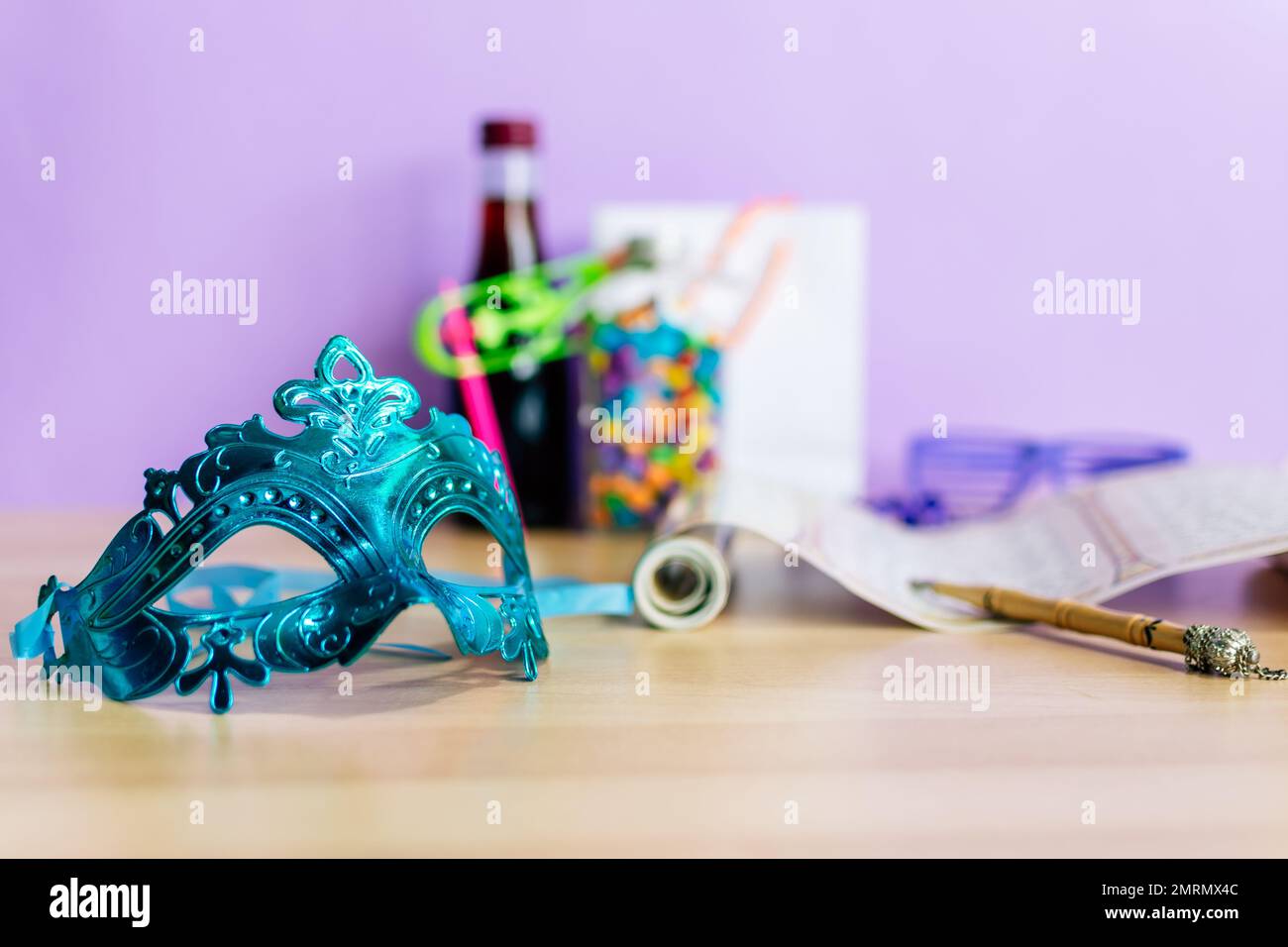 A blue masquerade mask with a pen and invitation for the celebration of ...