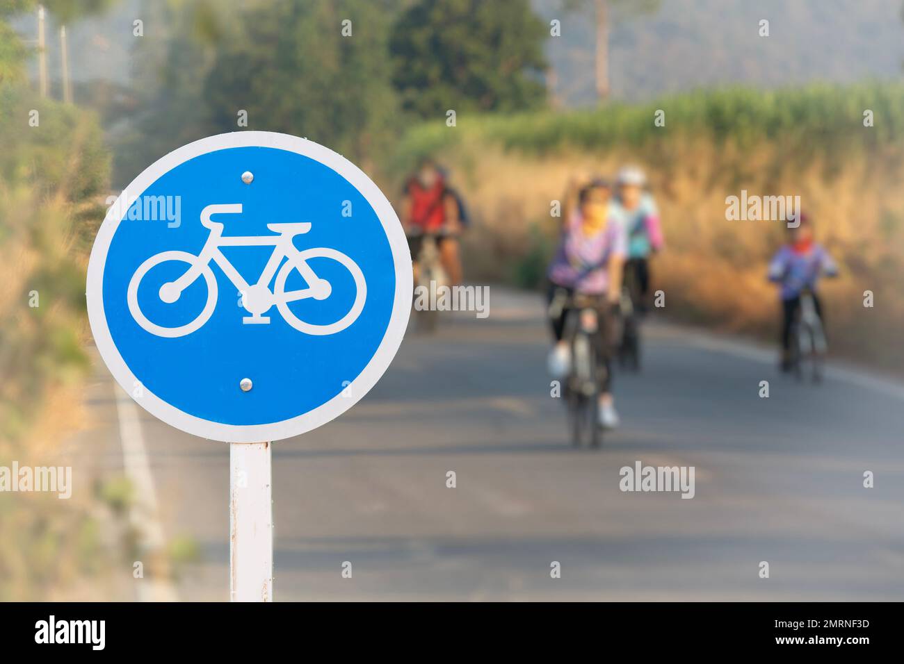 Bicycle traffic signs and people riding bicycles on rural roads in ...