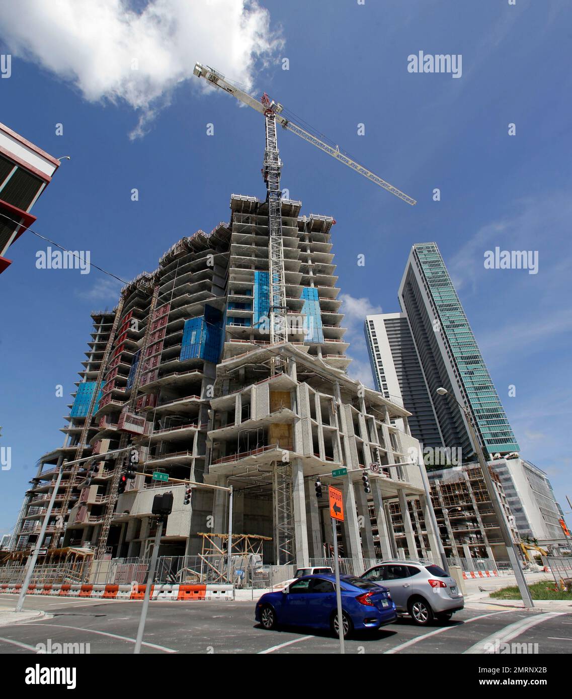 A high-rise building under construction is shown next to a high-rise ...