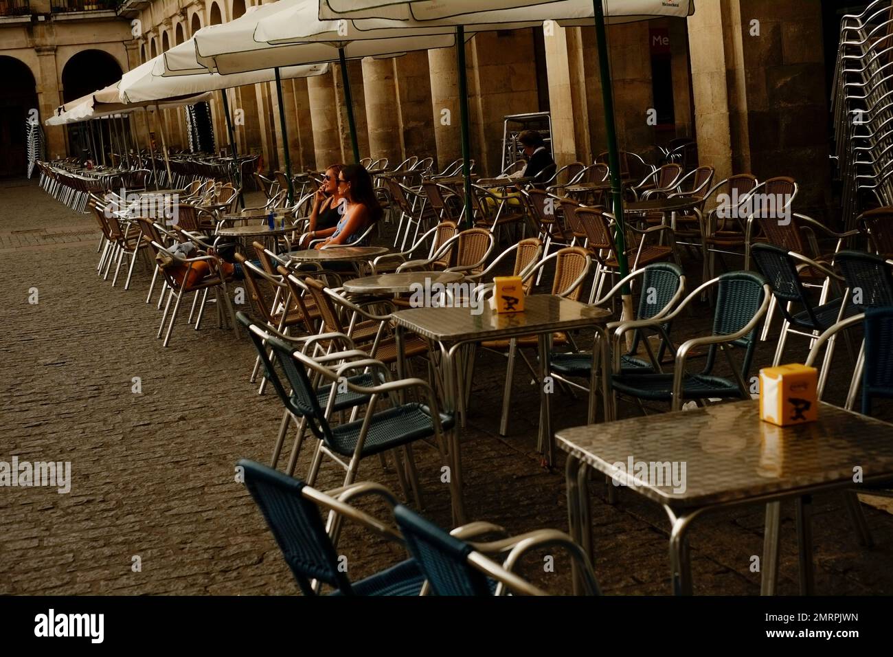 Two women rest while sitting outside of an empty bar terrace at Plaza ...