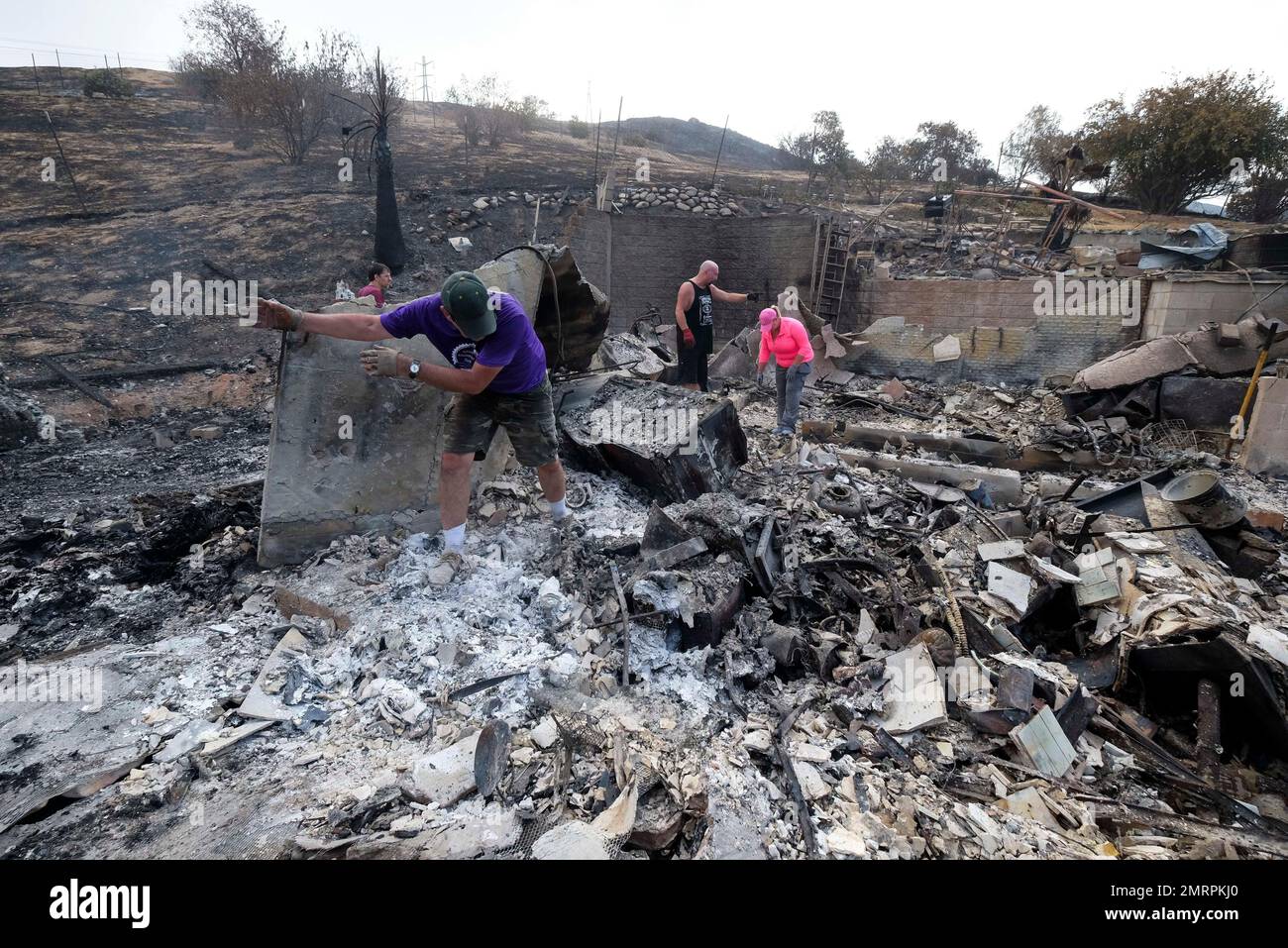 Friends of the home owner survey the charred debris left in a burned ...
