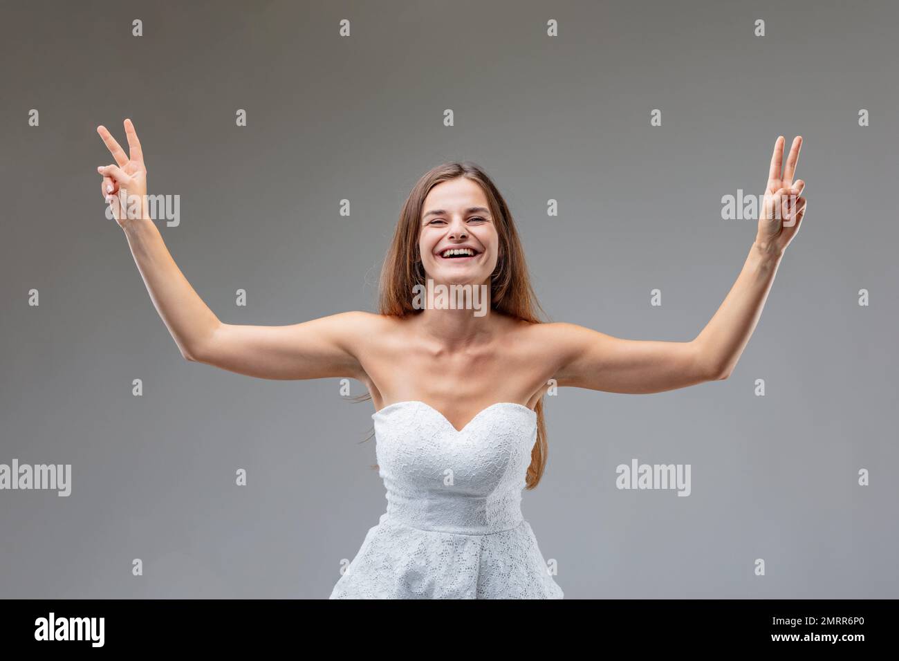 Happy girl raises her hands with victory signs wearing her white ...