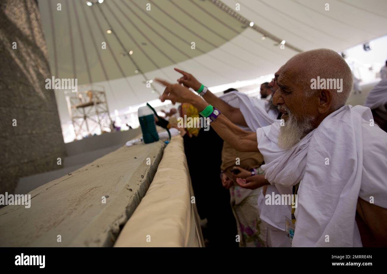 Muslim pilgrims cast stones at the huge stone pillar in the symbolic ...