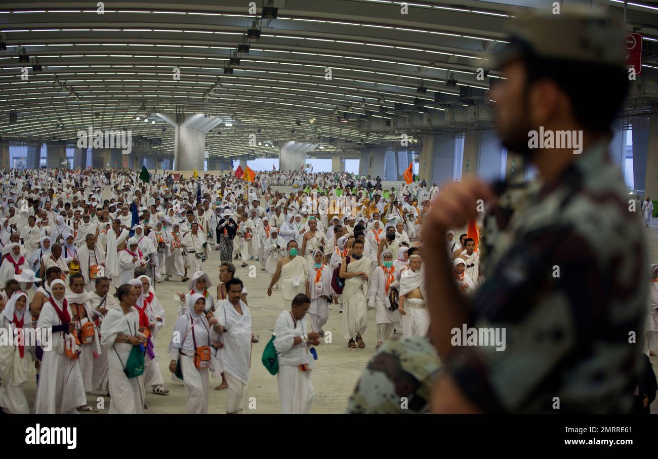Muslim pilgrims walk on the way to cast stones at the huge stone pillar ...