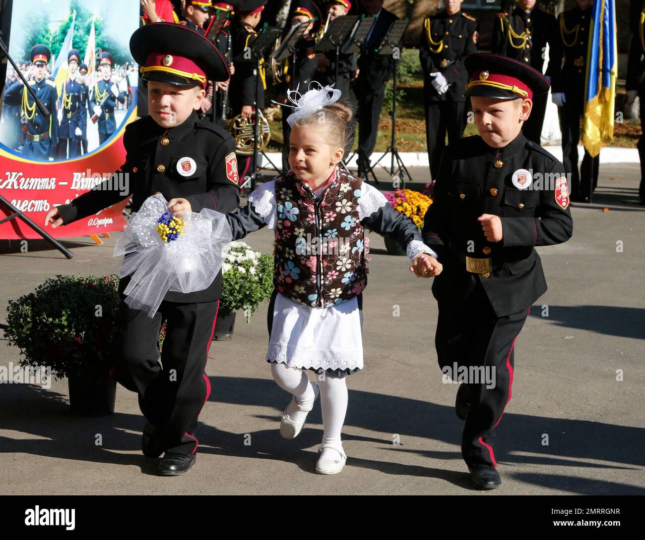 New cadets, a girl and two boys, run as they ring a symbolic bell at a ...