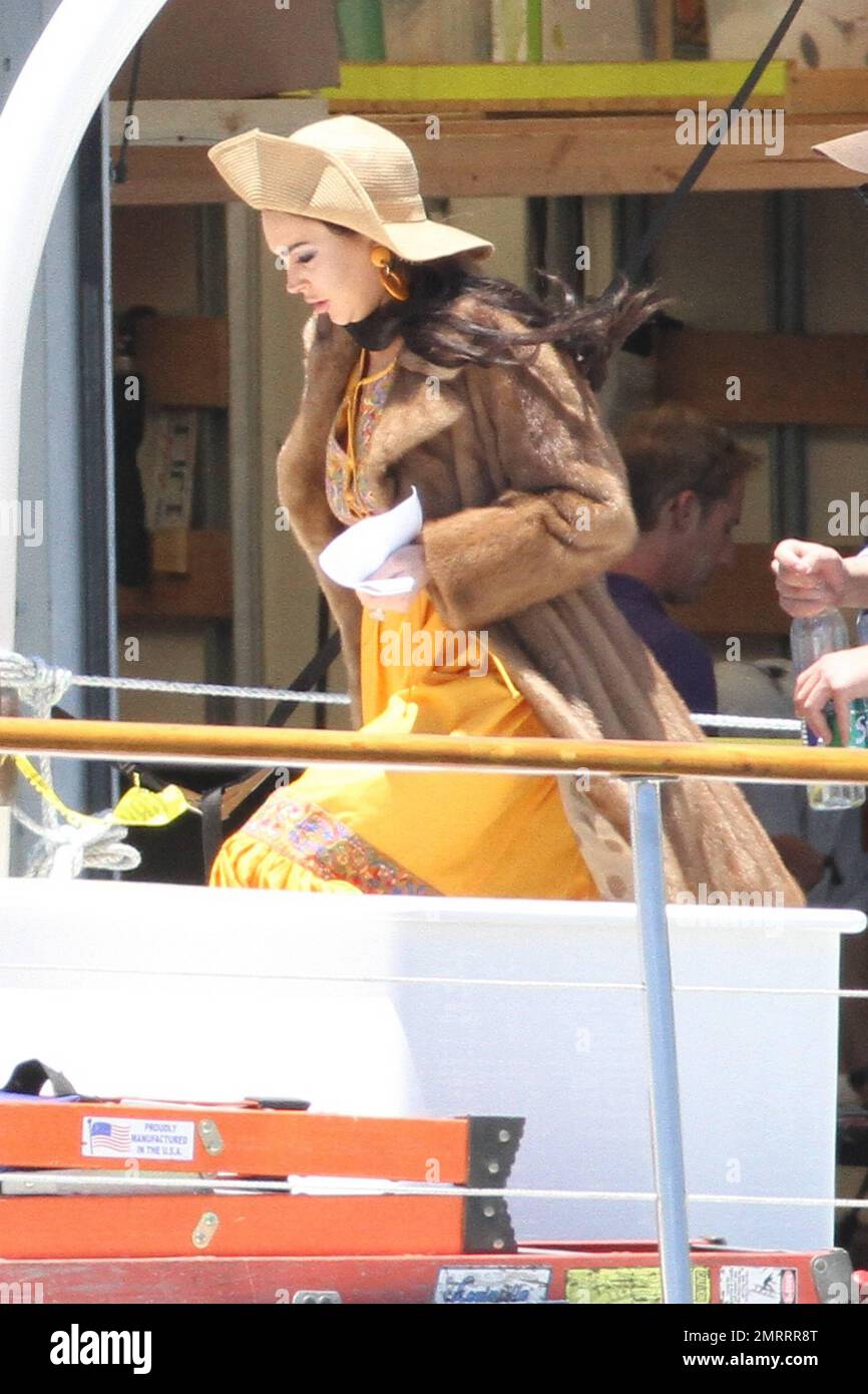 Smoking a cigarette, Lindsay Lohan portrays Elizabeth Taylor, wearing a ...