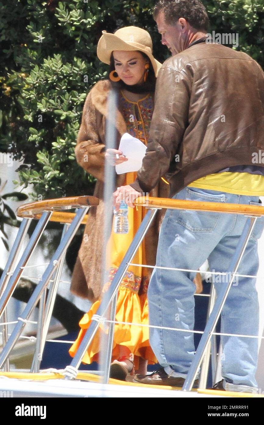 Smoking a cigarette, Lindsay Lohan portrays Elizabeth Taylor, wearing a ...