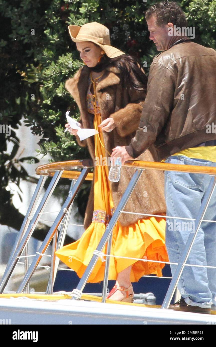 Smoking a cigarette, Lindsay Lohan portrays Elizabeth Taylor, wearing a ...