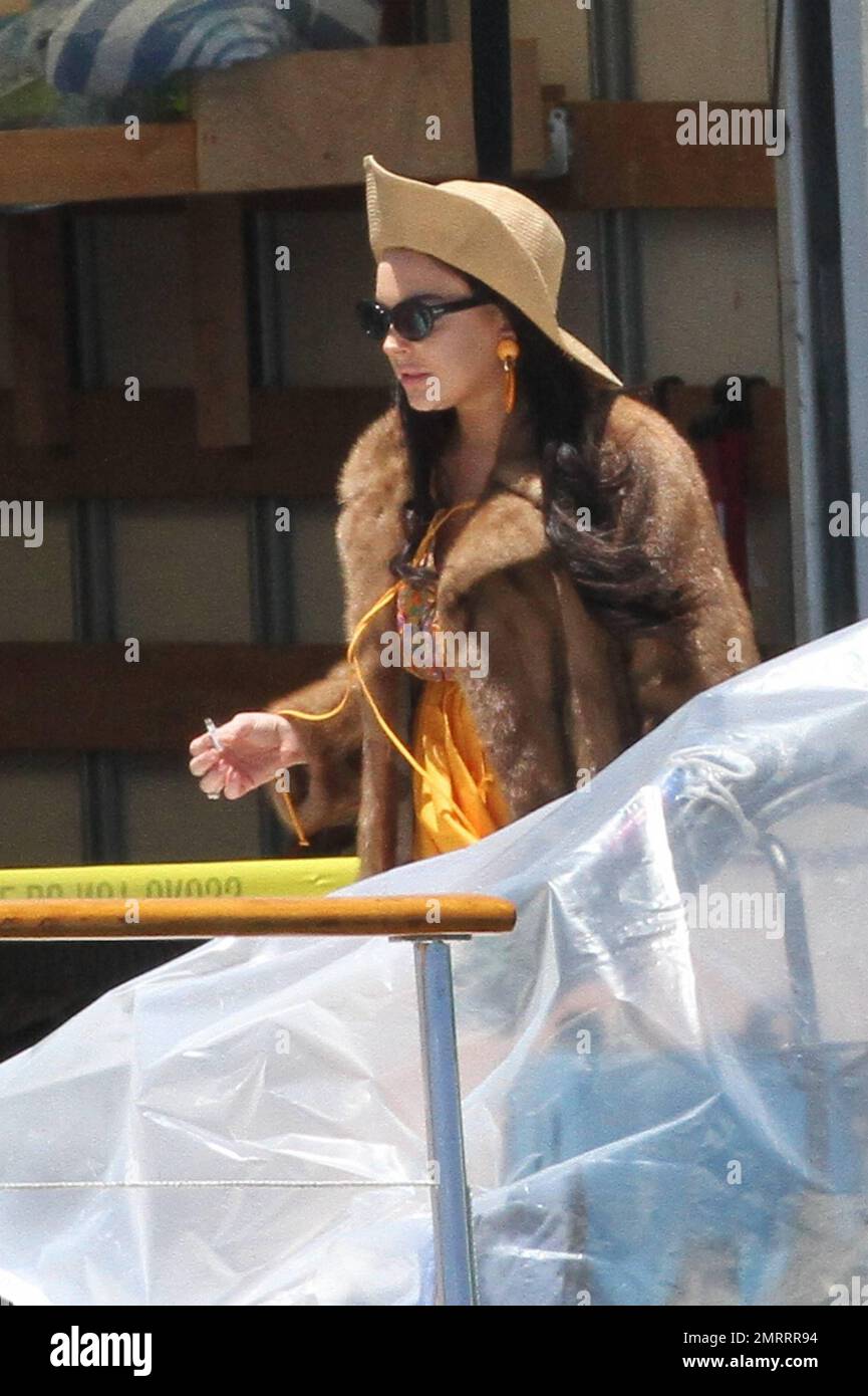 Smoking a cigarette, Lindsay Lohan portrays Elizabeth Taylor, wearing a ...