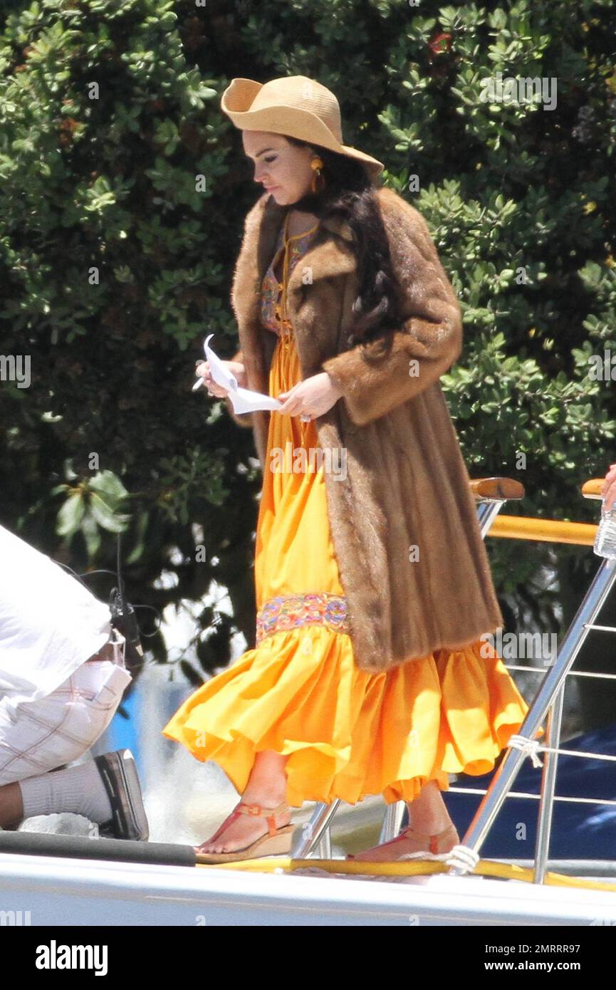 Smoking a cigarette, Lindsay Lohan portrays Elizabeth Taylor, wearing a ...