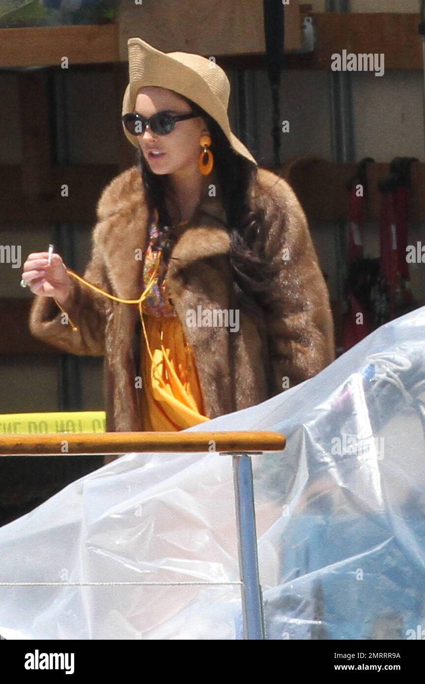 Smoking a cigarette, Lindsay Lohan portrays Elizabeth Taylor, wearing a ...