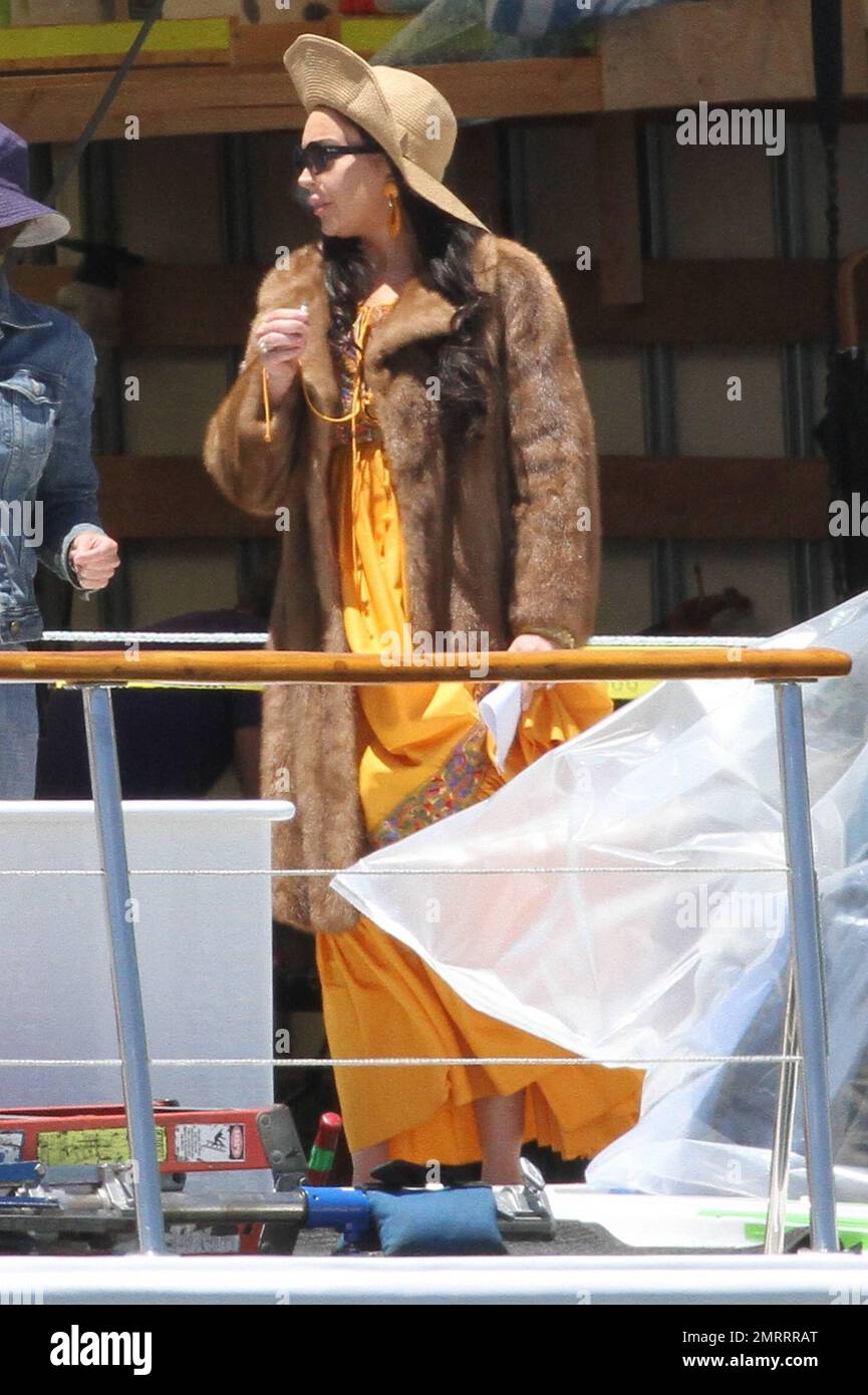 Smoking a cigarette, Lindsay Lohan portrays Elizabeth Taylor, wearing a ...