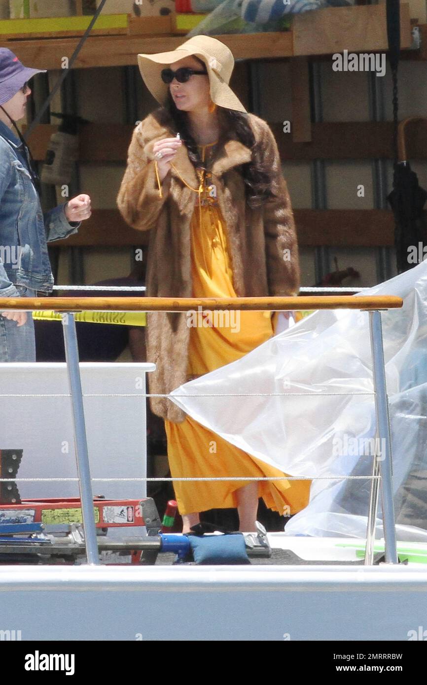 Smoking a cigarette, Lindsay Lohan portrays Elizabeth Taylor, wearing a ...