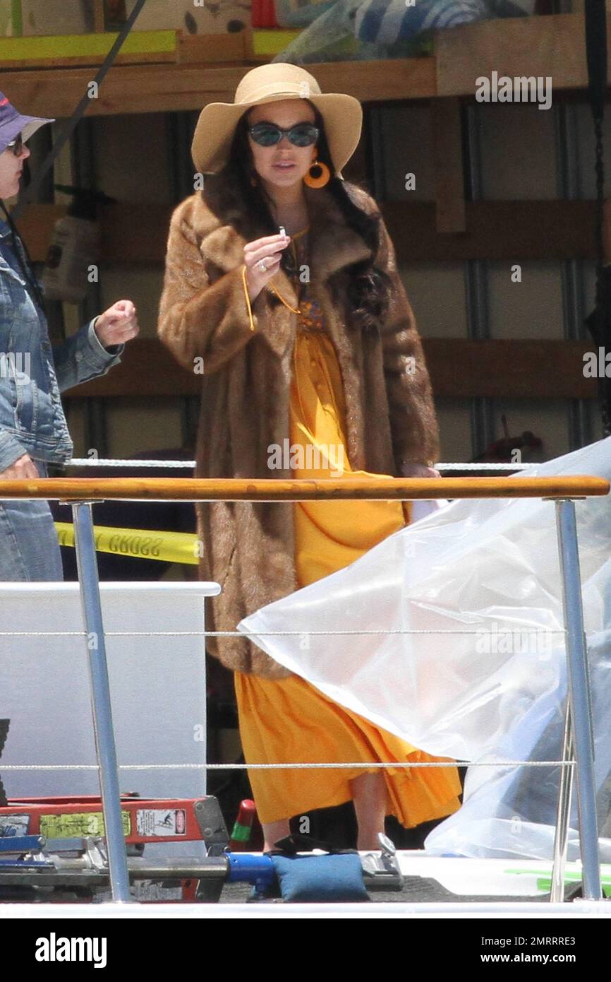 Smoking a cigarette, Lindsay Lohan portrays Elizabeth Taylor, wearing a ...