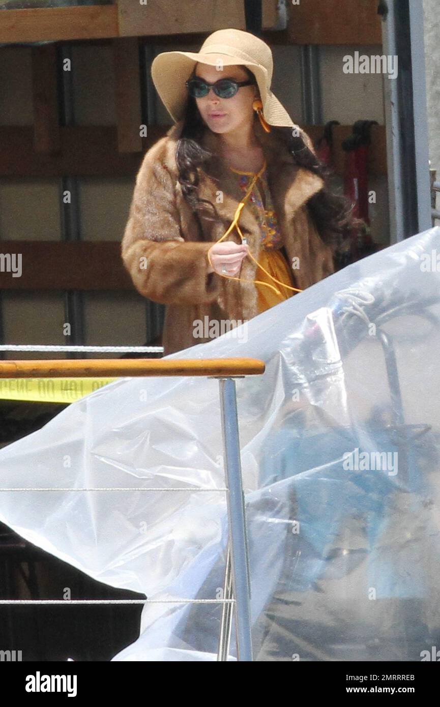 Smoking a cigarette, Lindsay Lohan portrays Elizabeth Taylor, wearing a ...