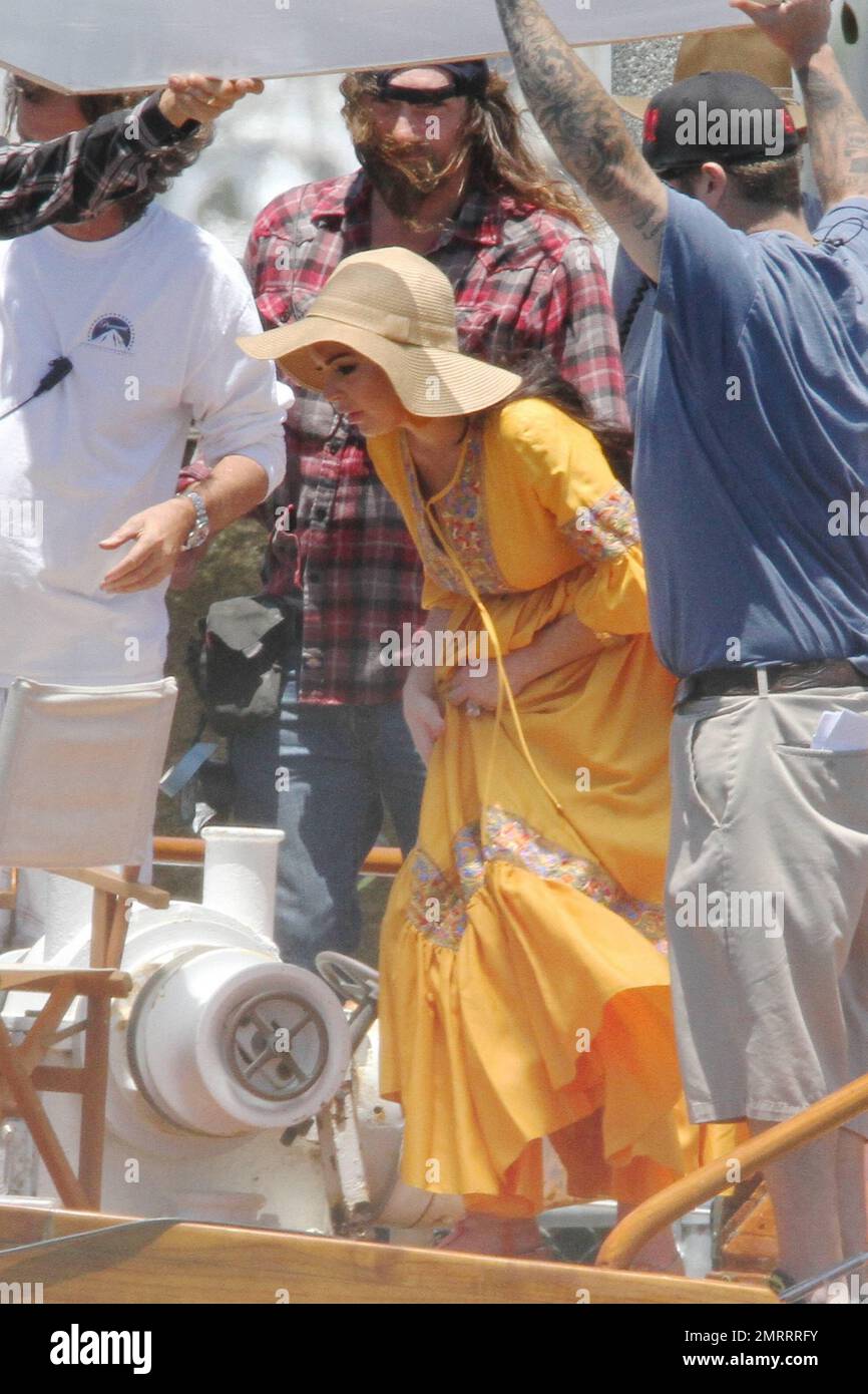 Smoking a cigarette, Lindsay Lohan portrays Elizabeth Taylor, wearing a ...