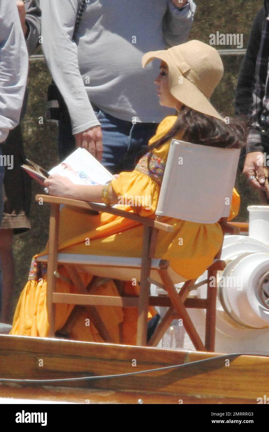 Smoking a cigarette, Lindsay Lohan portrays Elizabeth Taylor, wearing a ...