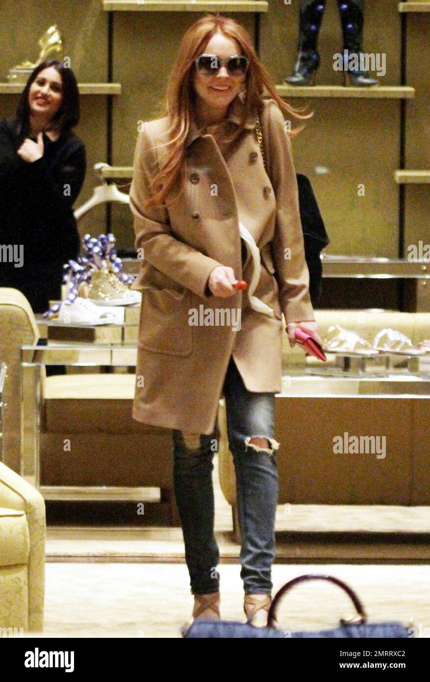 Wearing a tan coat and ripped jeans, actress Lindsay Lohan carries a ...
